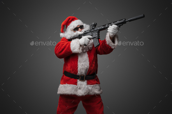 Santa gunslinger with rifle posing against grey background Stock Photo ...