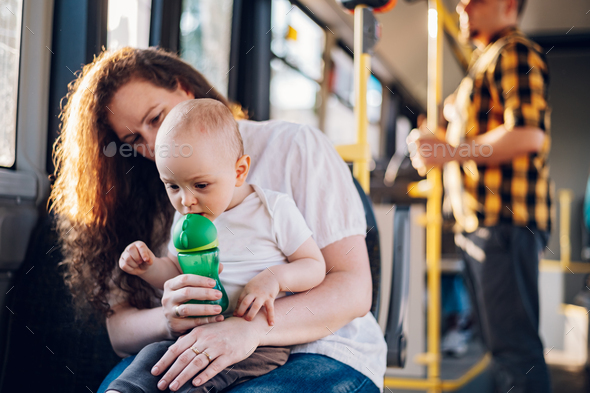Happy mother and son riding in bus while baby sits in her lap. Stock ...