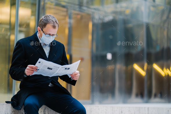 serious man boss takes break after walking, reads newspaper, wears ...