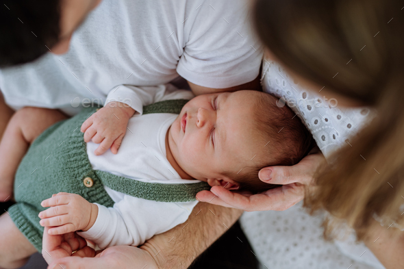 Happy parents cuddling with their newborn baby. Stock Photo by halfpoint