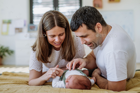 Happy parents cuddling with their newborn baby. Stock Photo by halfpoint