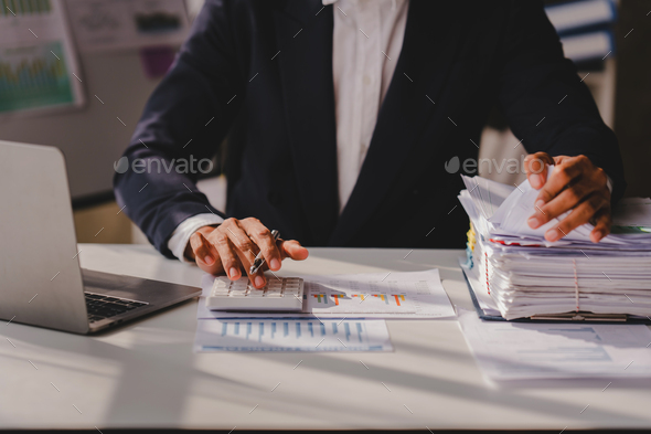 work from office A businessman works a bunch of paper files to find ...