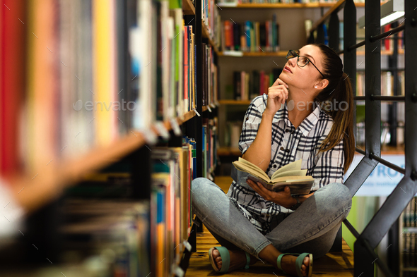 Young female student study in the library reading book while sitting ...