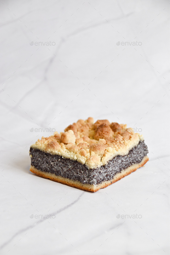 a piece of traditional German poppy seed crumble cake on white marble ...