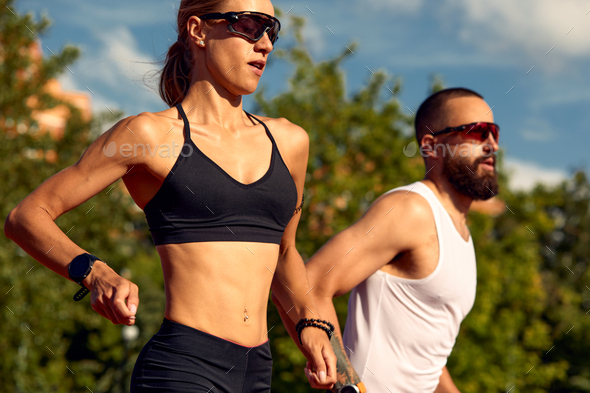 Young family promoting healthy lifestyle. Woman and man run stadium. Coach and sportsman motion ...