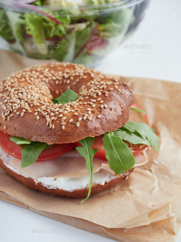 bagel filled with rocket, turkey ham, cream cheese and tomato on ...