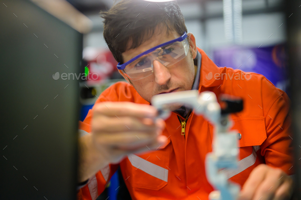 Professional technician checking and repairing parts of robotic machine ...