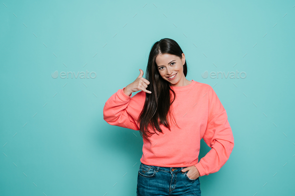 Smiling delighted brunette woman makes phone gesture, shows call me ...