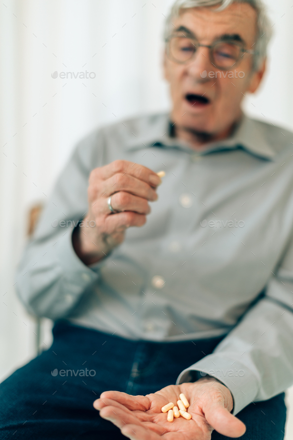 pills medicine on the hand of an old man taking pill. Senior person ...