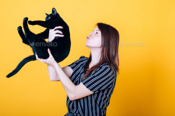 happy cheerful woman playing with a young black cat Stock Photo by carlo_p