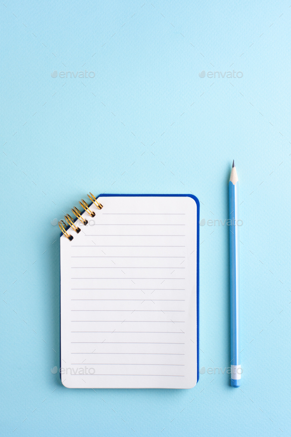Vertical background with note book paper page and blue sharp pencil on ...