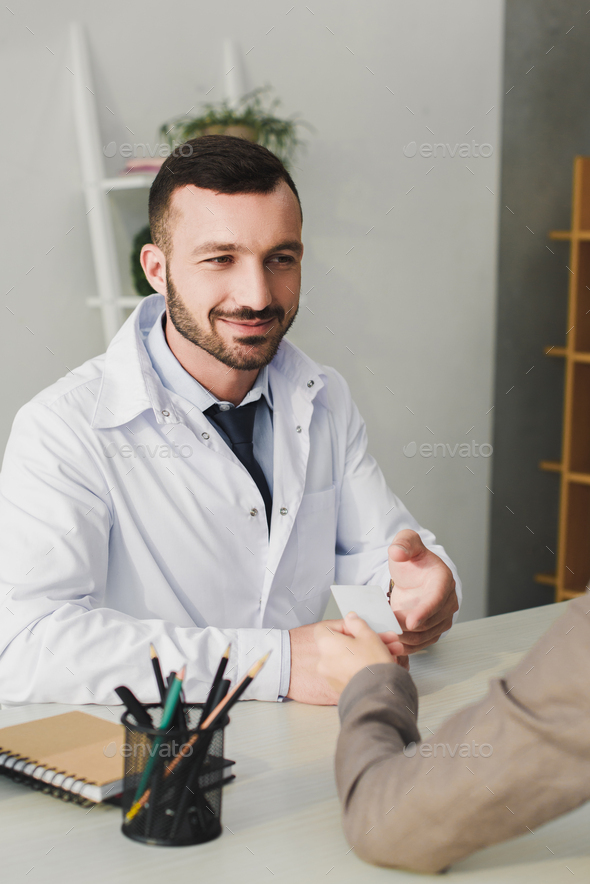 patient giving id card to smiling doctor in clinic Stock Photo by ...