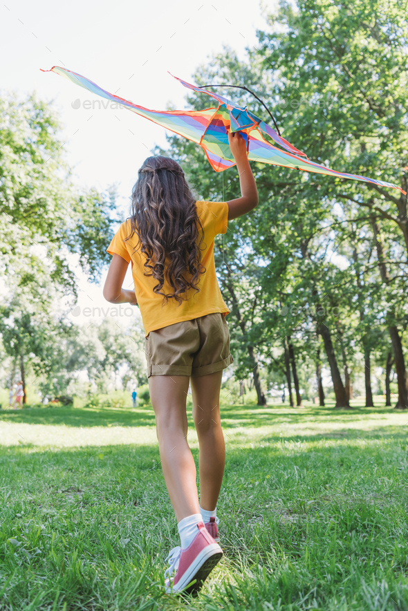 back view of cute child playing with colorful kite in park Stock Photo ...