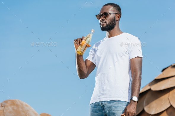 handsome african american man drinking soda against blue sky Stock ...