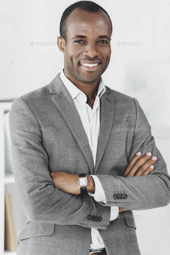 smiling african american man with crossed arms looking at camera Stock Photo by LightFieldStudios