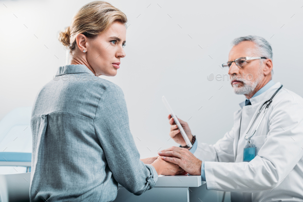 serious male doctor with digital tablet cheering up and holdings hands ...