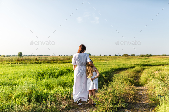 rear view of mother and daughter standing on path in green meadow Stock ...