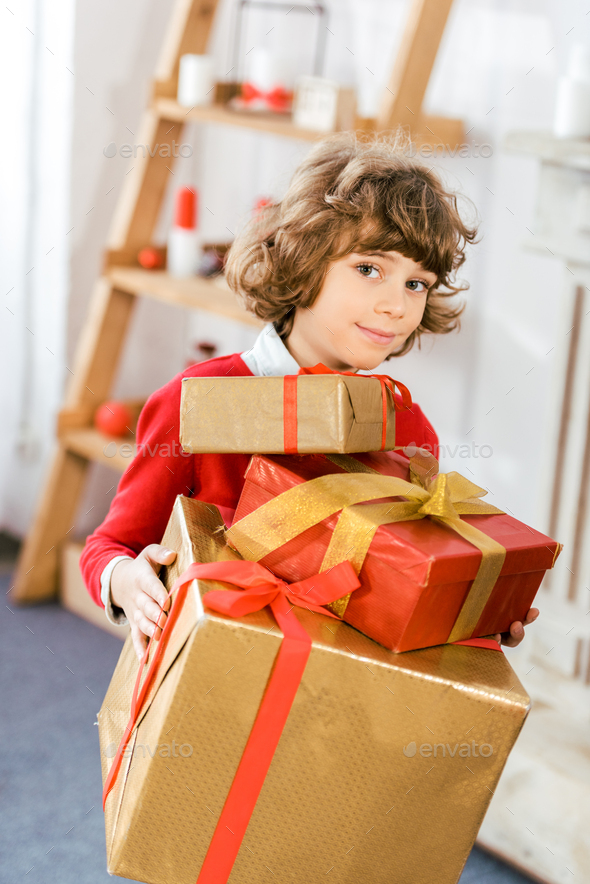 adorable happy kid holding stack of christmas gift boxes Stock Photo by ...