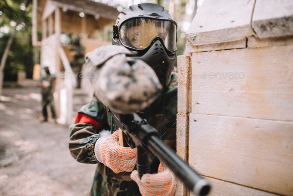 selective focus of male paintballer in goggle mask covered by paintball ...
