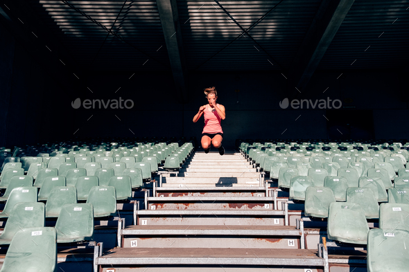 front view of fit and healthy woman workingout at the stadium jumping ...