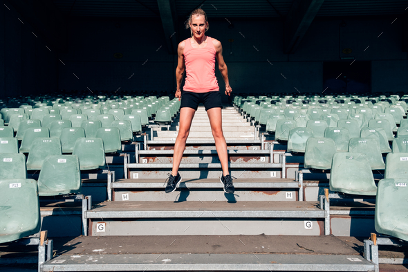 front view of fit and healthy woman workingout at the stadium jumping ...