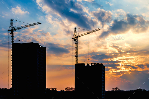 silhouette of tower cranes and unfinished multi-storey high buildings ...