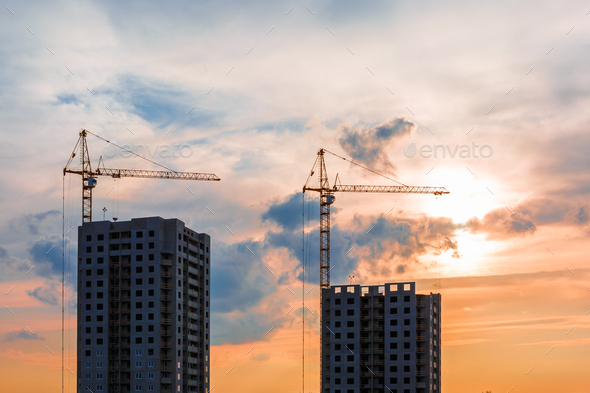 silhouette of tower cranes and unfinished multi-storey high buildings ...