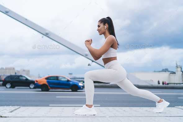 Young happy woman makes deep forward lunges to pump muscles of the legs ...