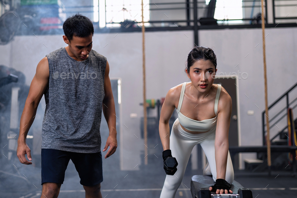 Male fitness center instructor help woman lifting dumbbell workout at ...