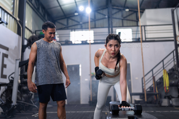 Male fitness center instructor help woman lifting dumbbell workout at ...