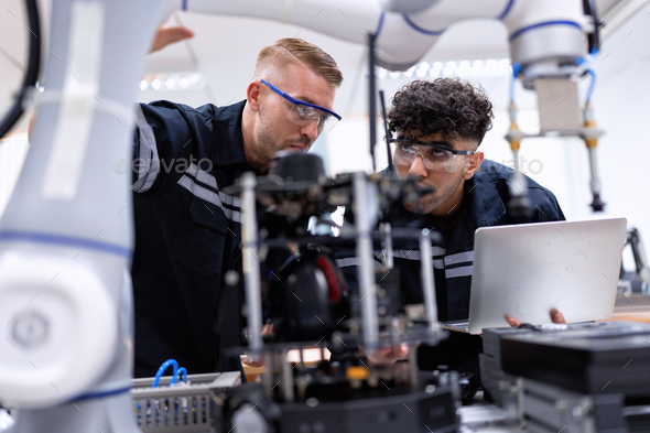 Engineer sitting in robot fabrication room quality checking robot arm ...