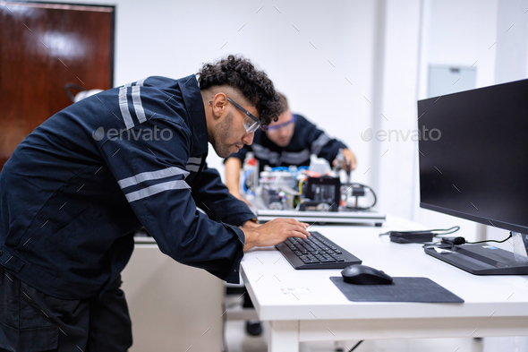Engineer sitting in robot fabrication room quality checking electronic ...