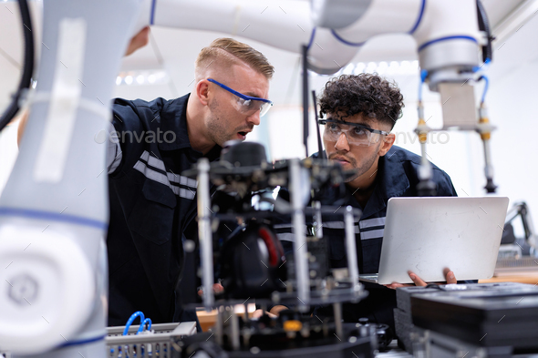 Engineer sitting in robot fabrication room quality checking robot arm ...