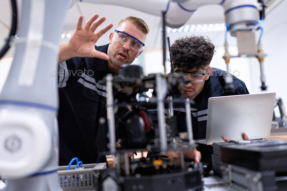 Engineer sitting in robot fabrication room quality checking robot arm ...