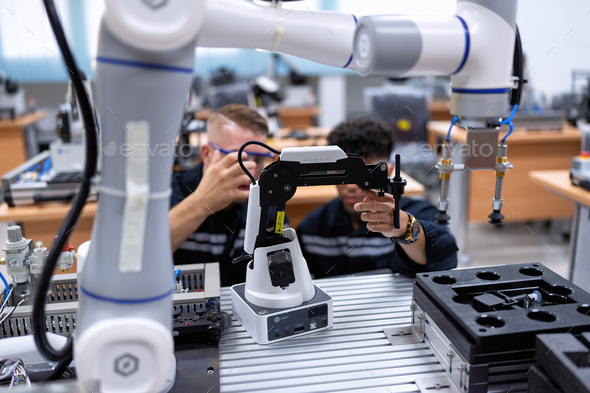 Engineer sitting in robot fabrication room quality checking robot arm ...