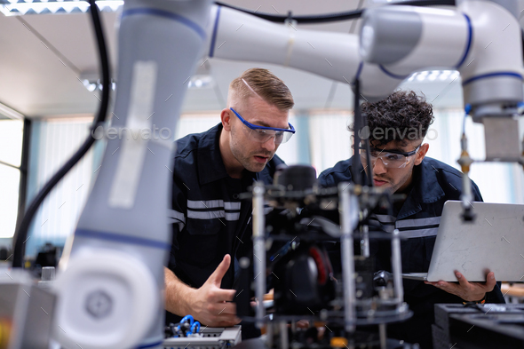 Engineer sitting in robot fabrication room quality checking robot arm ...