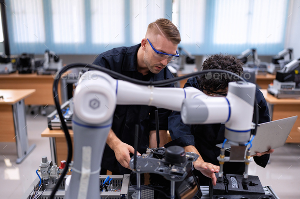 Engineer sitting in robot fabrication room quality checking robot arm ...