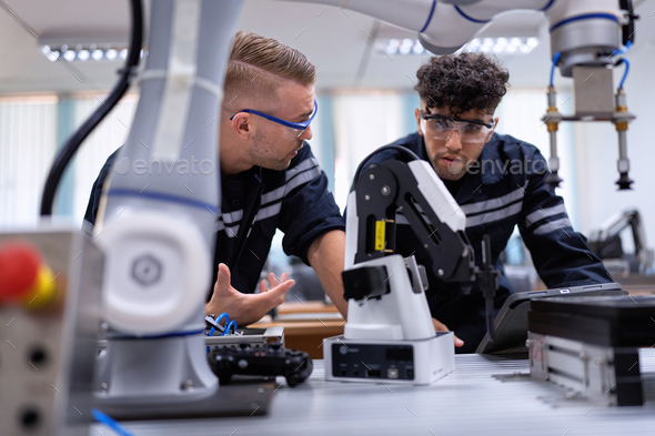 Engineer sitting in robot fabrication room quality checking robot arm ...
