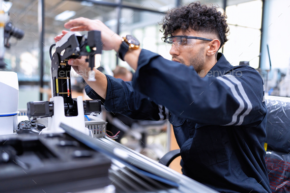 Engineer sitting in robot fabrication room quality checking robot arm ...