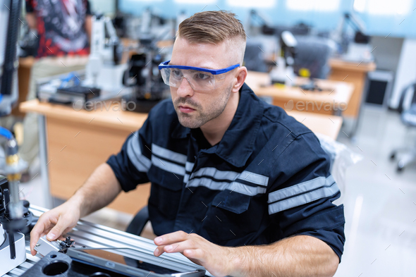 Engineer sitting in robot fabrication room quality checking robot arm ...