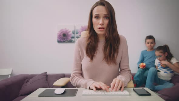 Mother Working on Computer at Home with Kids Playing on Background ...