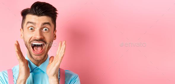 Close-up of happy caucasian guy screaming of joy and surprise, checking ...