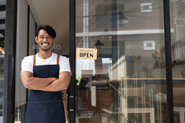 Portrait of smiling owner standing at his restaurant gate with open ...