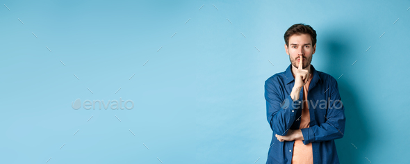 Modern guy shushing at camera, press finger to lips and telling a ...