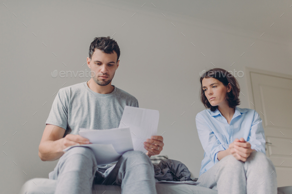 couple study documents together at bed, have serious looks, plan thier ...