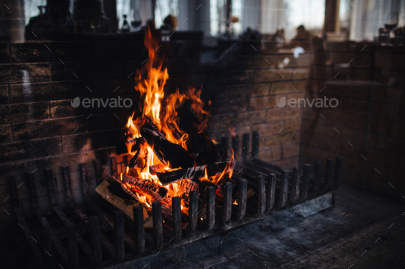 Blazing fire against brick wall background. Dark colours. Burning wood ...