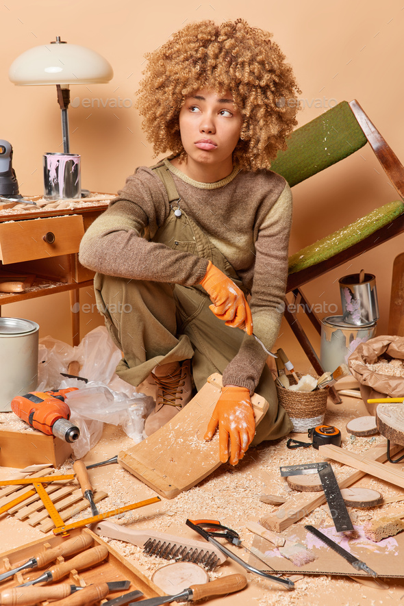 Vertical shot of displeased curly haired professional female carpenter ...