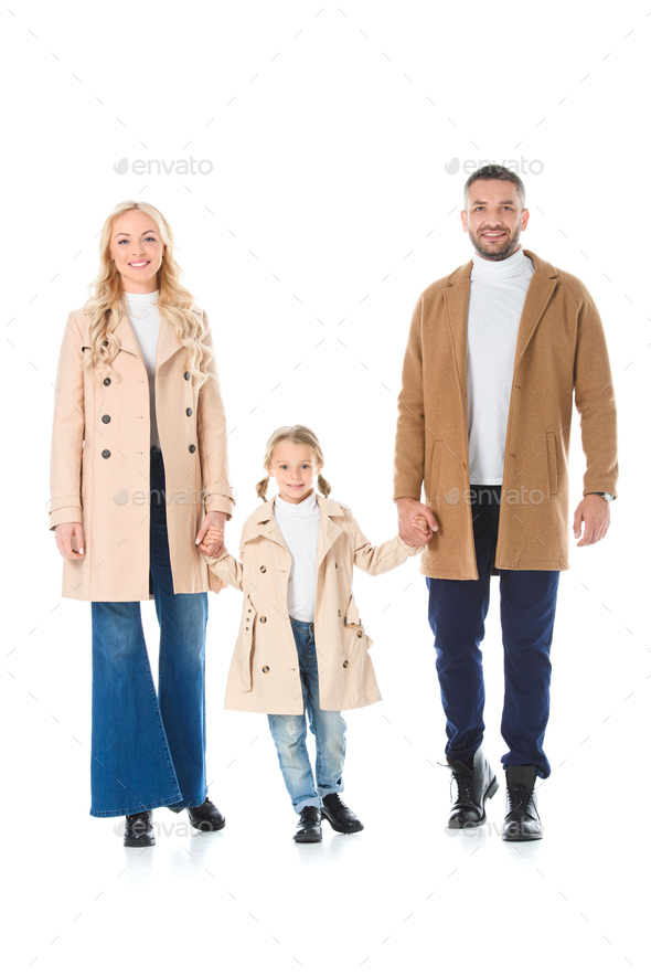 happy parents holding hands with adorable daughter and posing in beige ...