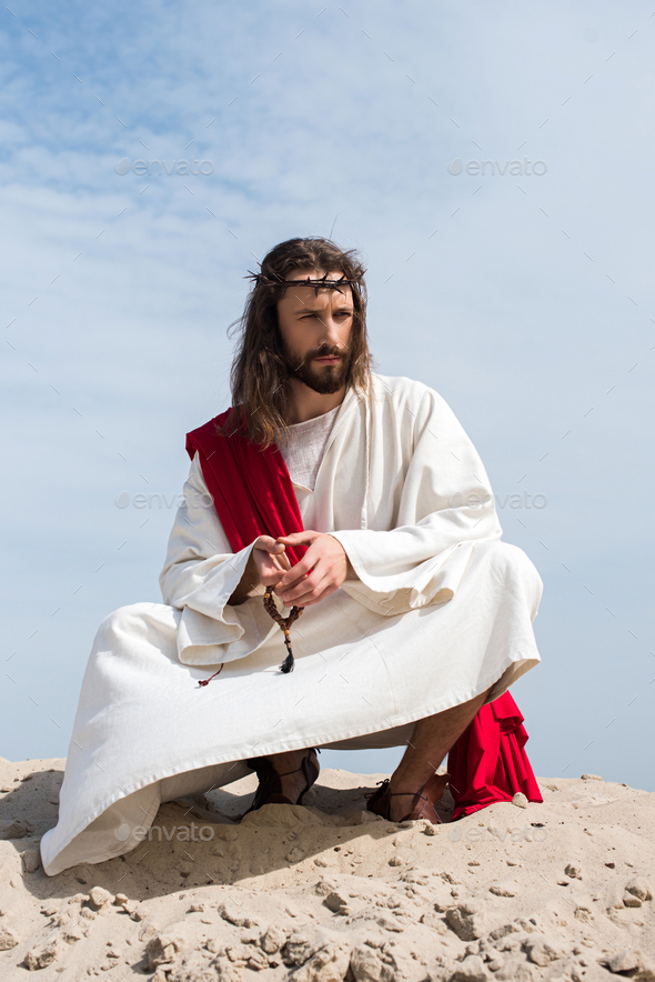 Jesus in robe, red sash and crown of thorns praying with rosary and ...