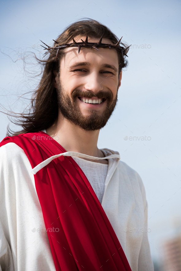 portrait of smiling Jesus in robe, red sash and crown of thorns ...